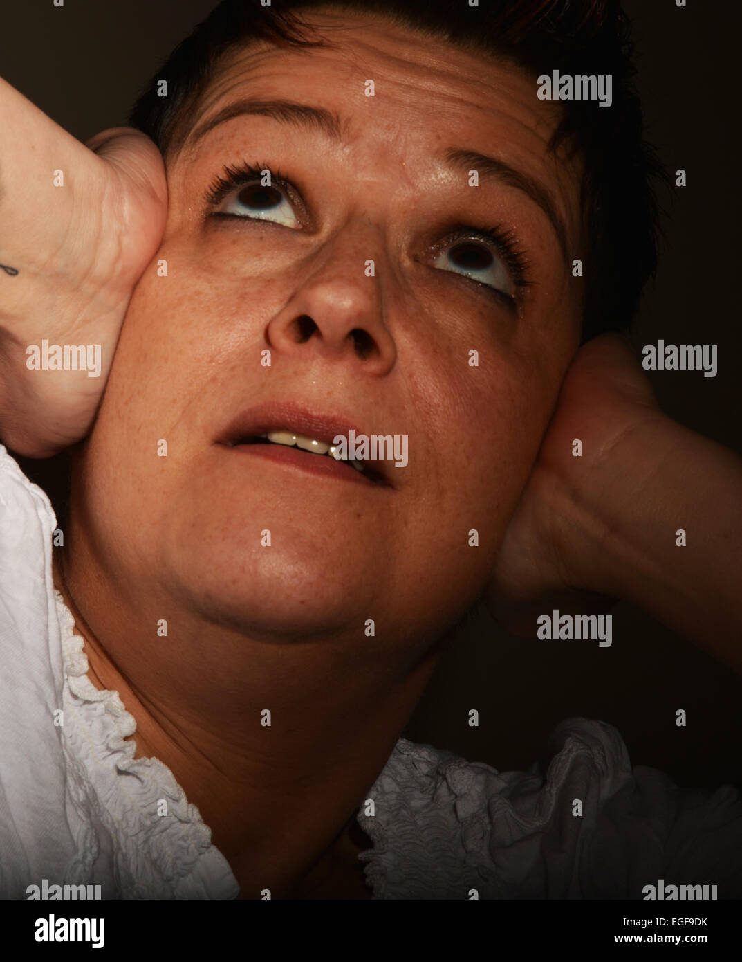 A young woman with a distressed face is holding her ears. Photo on 03 ...