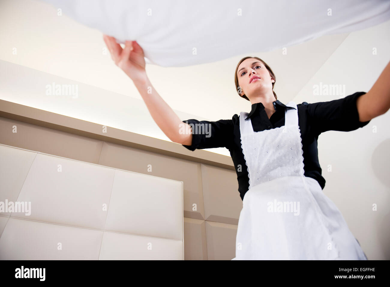 Maid making bed in hotel room Stock Photo - Alamy