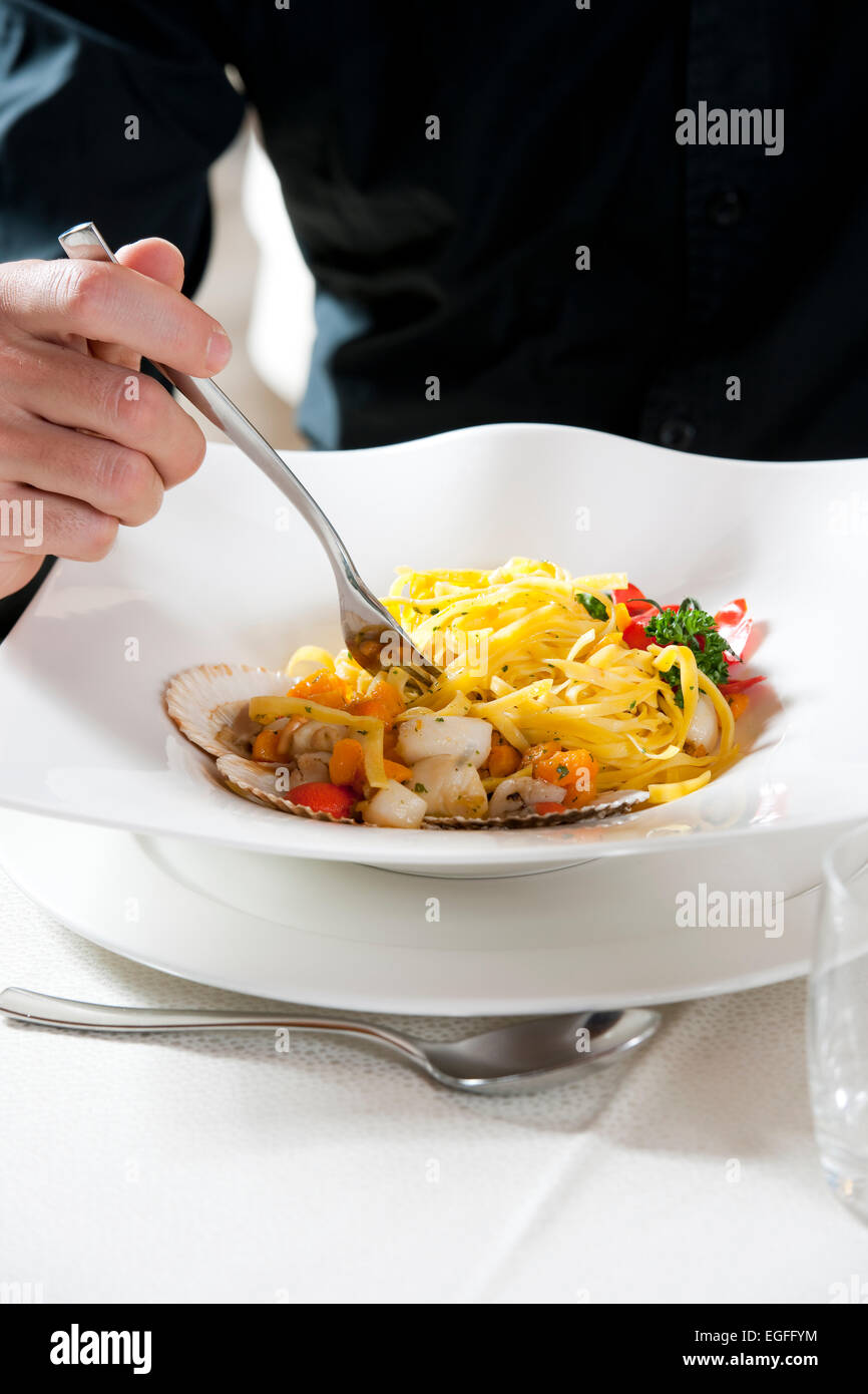 Man eating spaghetti with fish and vegetables Stock Photo - Alamy