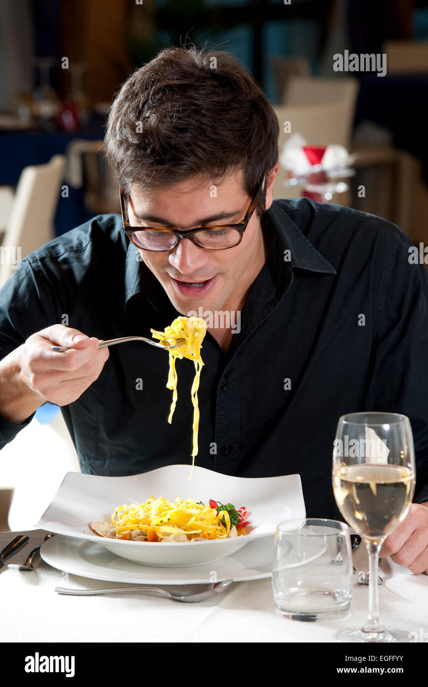 Man eating spaghetti with fish and vegetables Stock Photo - Alamy