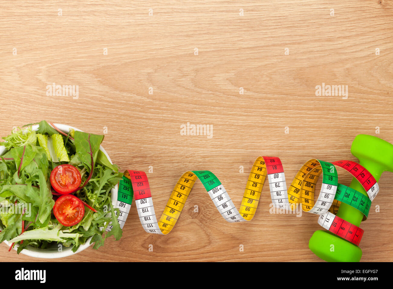 Dumbells, tape measure and healthy food over wooden table with copy ...