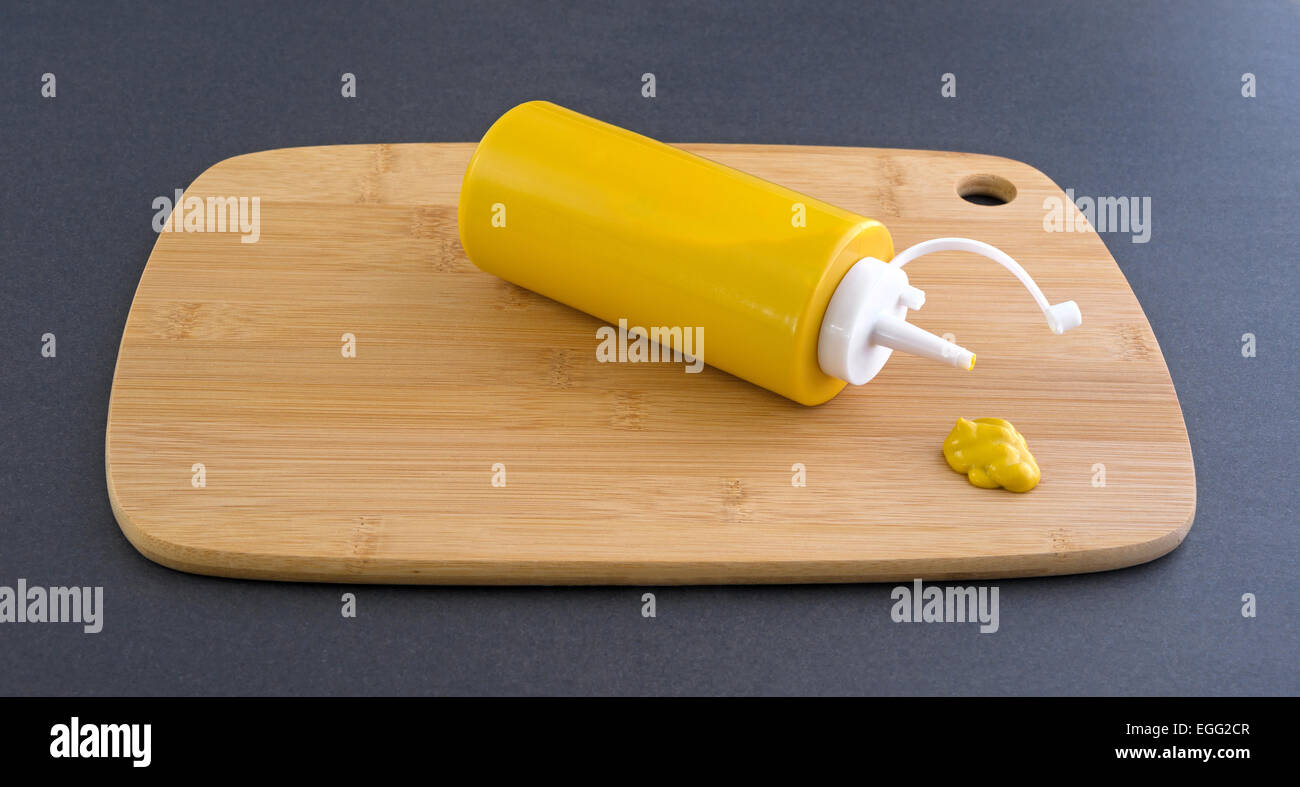 A bottle of mustard laying on its side with a small blob squeezed out ...