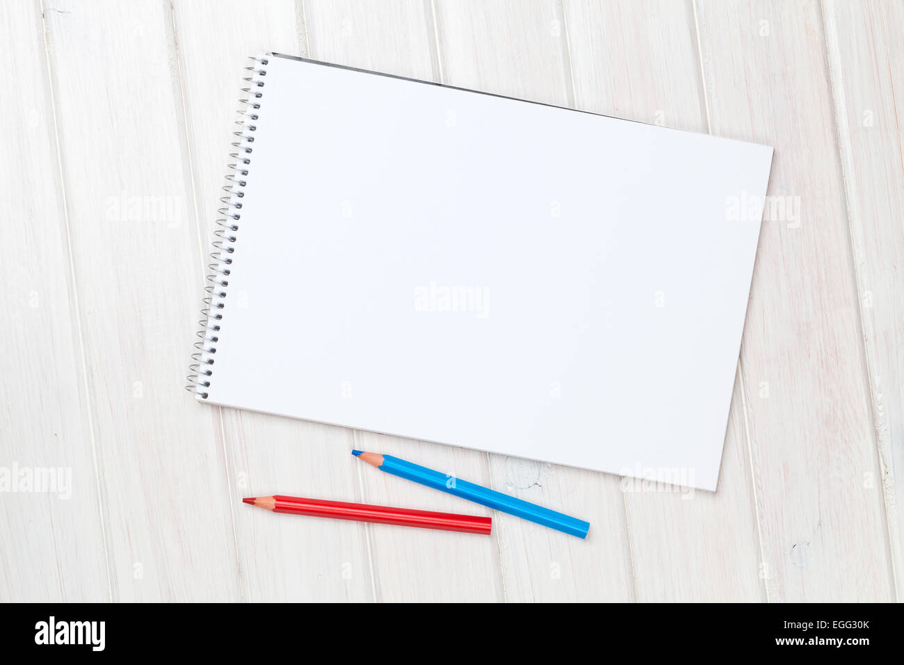Blank paper and colorful pencils on the wooden table. View from above ...