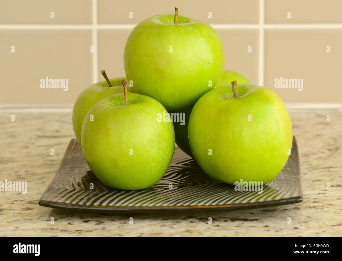Fresh ripe green apples in flat square plate on counter top Stock Photo ...