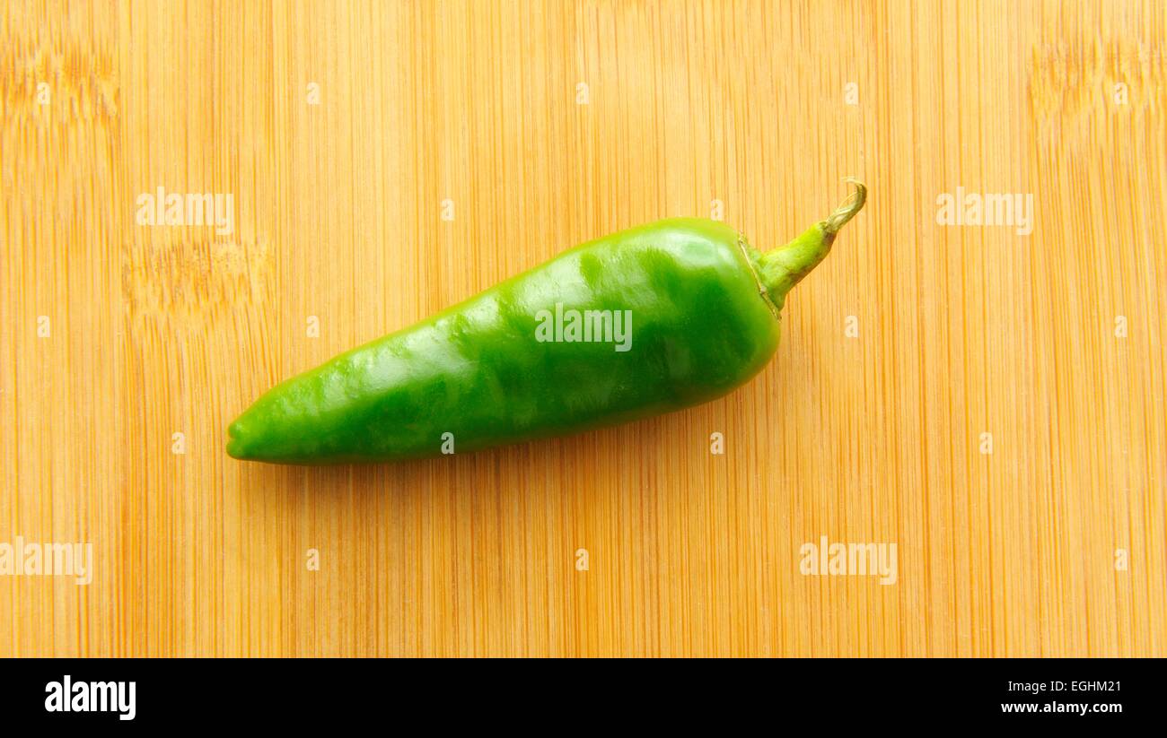 A single green chili pepper on a wooden background Stock Photo - Alamy