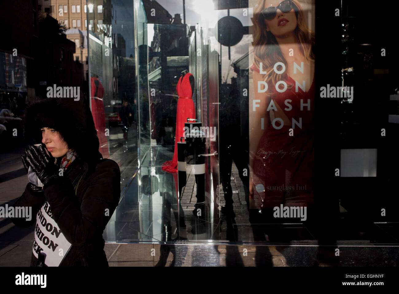 Passers-by and London Fashion Week red dress in central London window ...