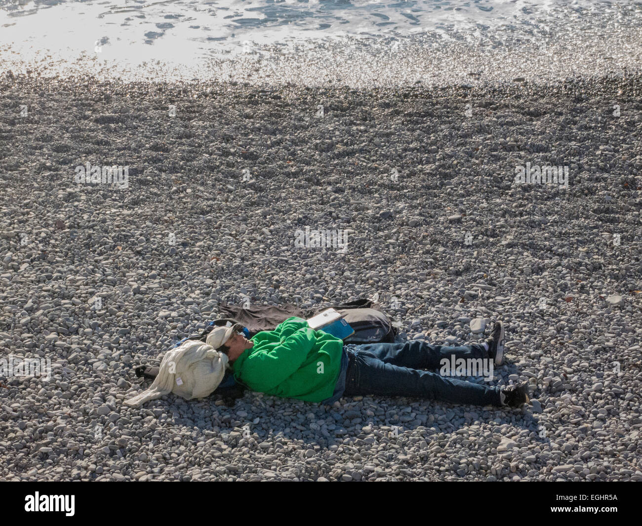 A man taking a nap on the beach in Nice, France, in the December sun ...