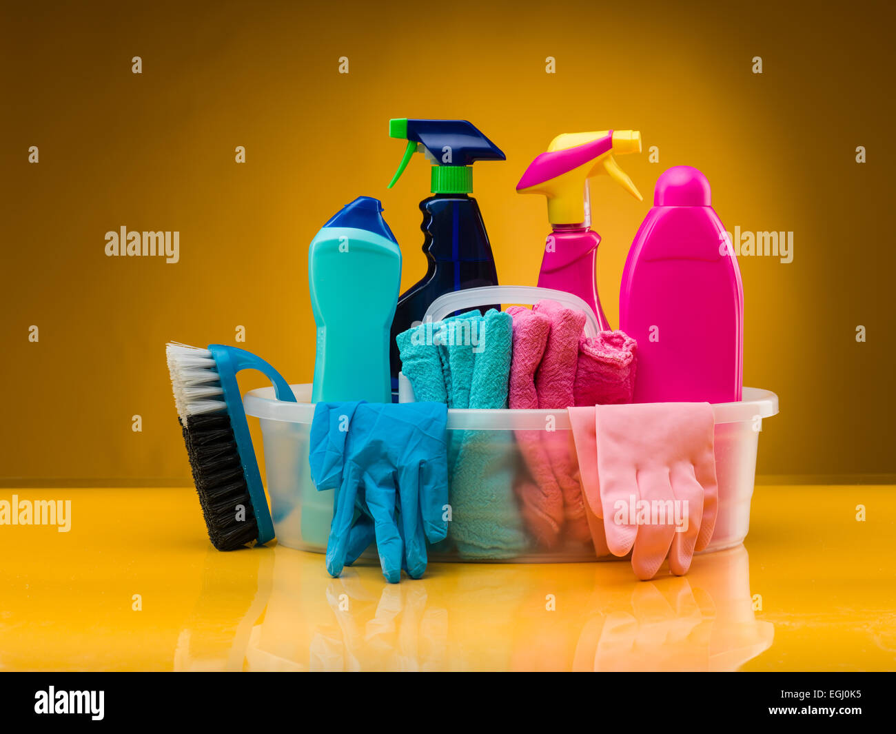 cleaning products and utensils in plastic basin against yellow ...