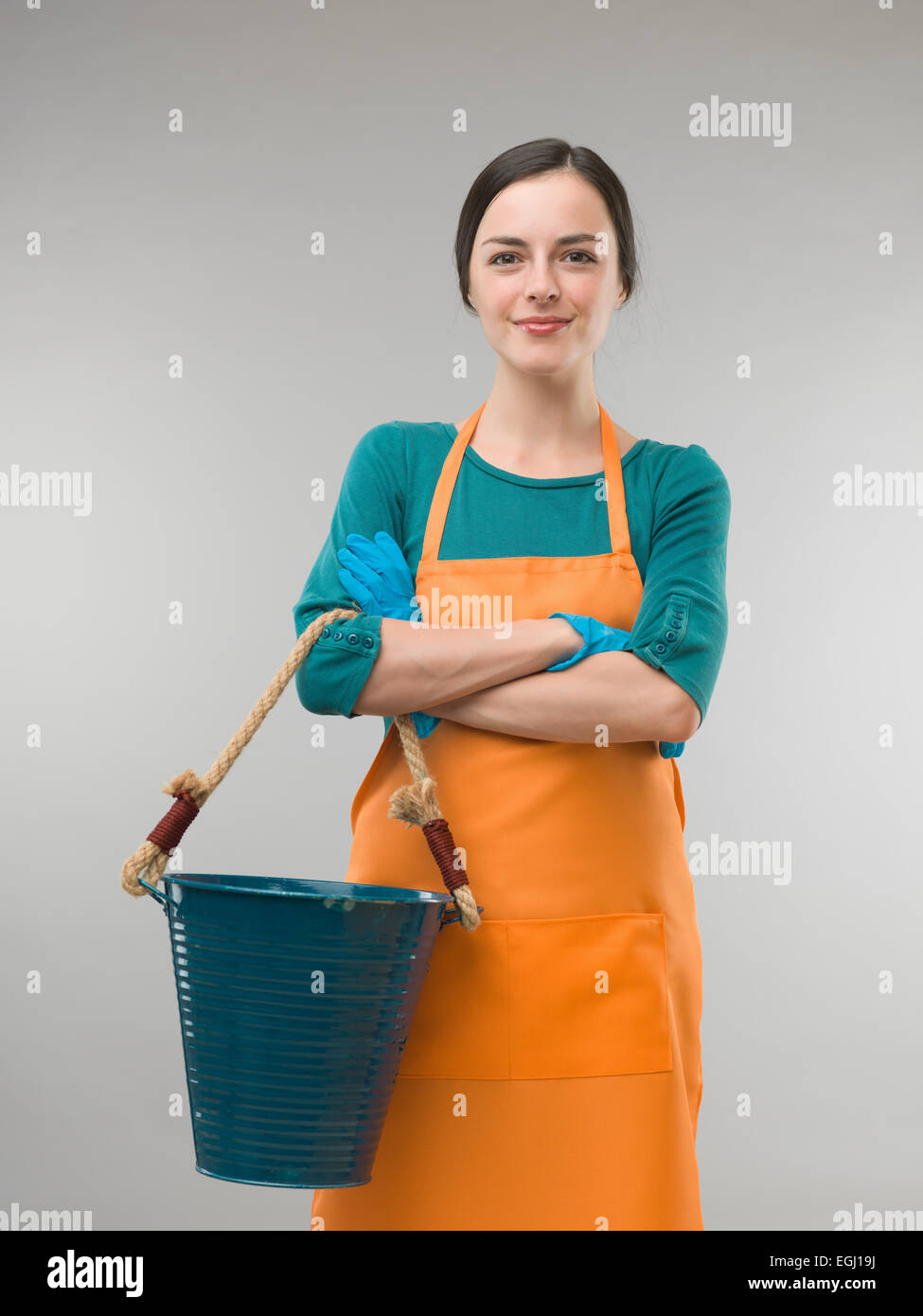 happy confident cleaning lady holding bucket with arms crossed, on grey ...