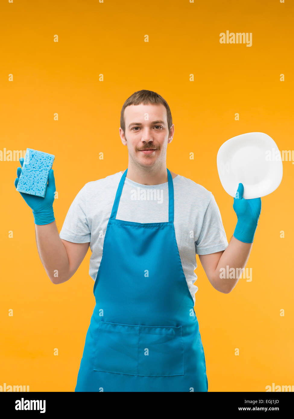 happy man in apron holding clean dishes and sponge, against yellow ...