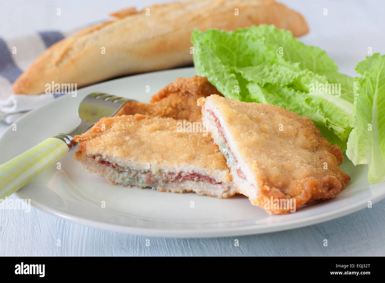 french deep fried cordon bleu with salad on white plate Stock Photo - Alamy