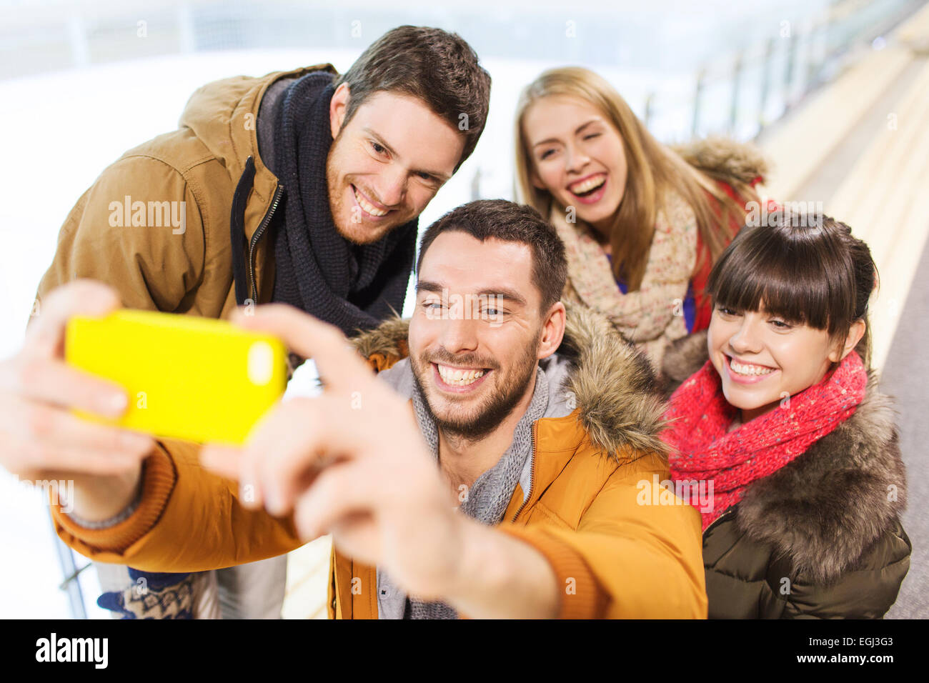 happy friends with smartphone on skating rink Stock Photo - Alamy