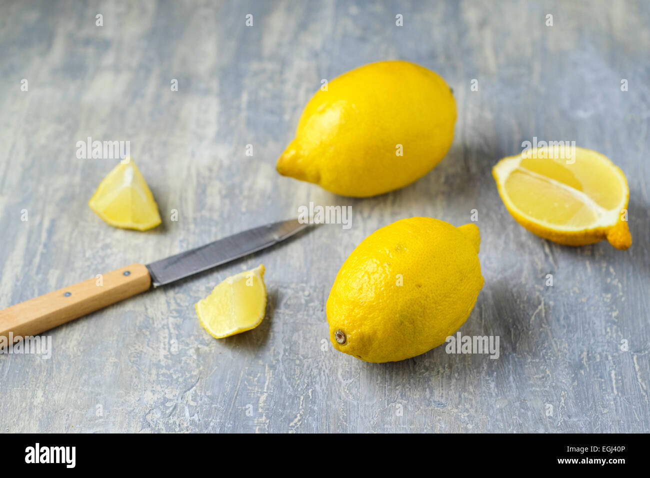 Whole lemons, lemon pieces and knife on a gray background Stock Photo ...
