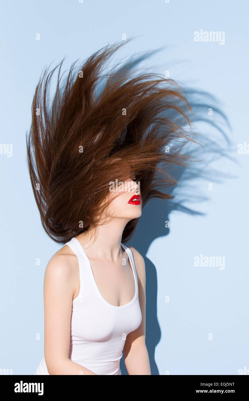 Young woman, head, hair, movement, blue background, side view, hair in ...