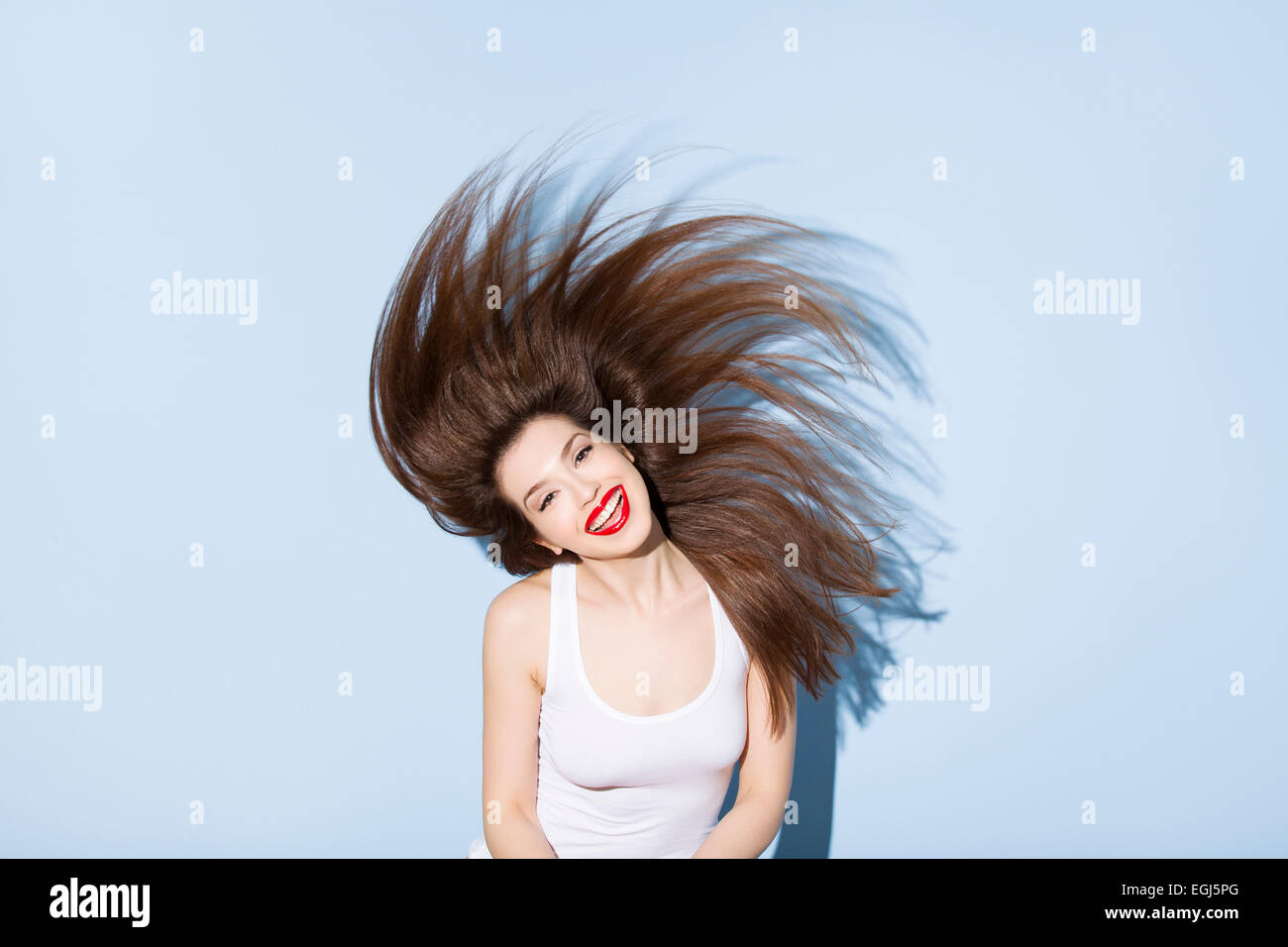Young woman, head, hair, movement, blue background Stock Photo - Alamy