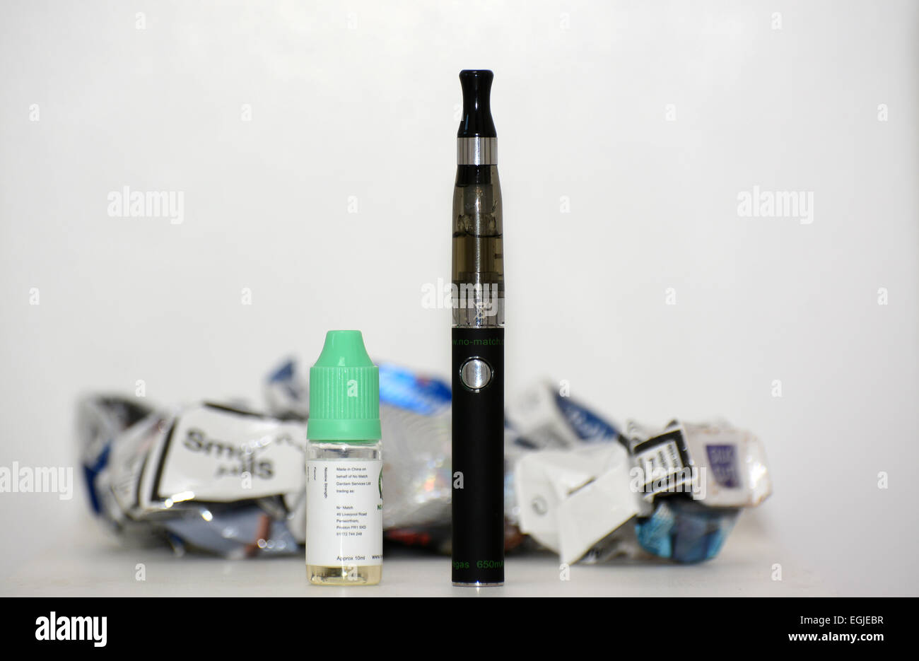 A typical e-cigarette with its fluid in front of discarded crumpled ...