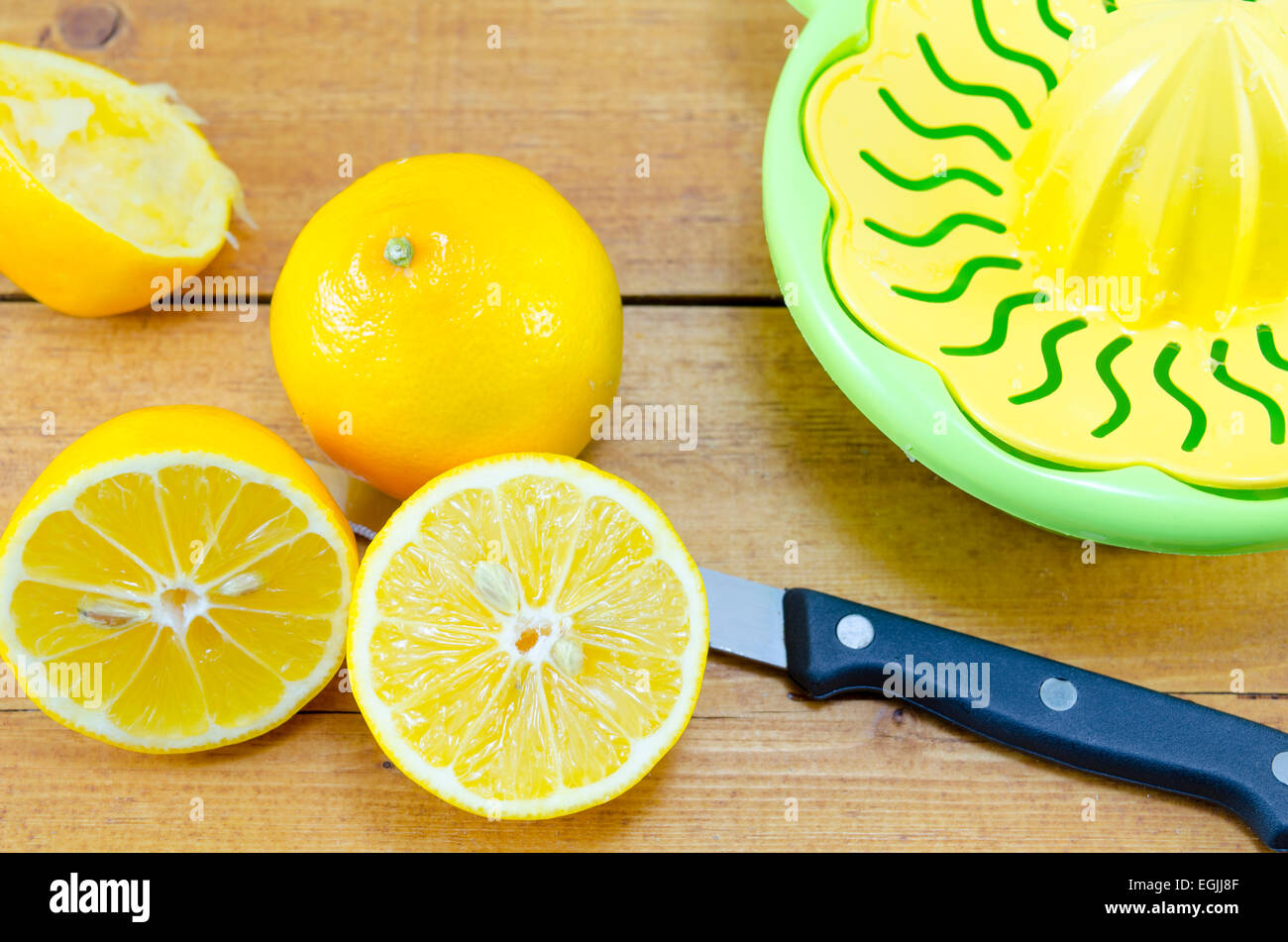 Whole, halved and squeezed lemons and a lemon squeezer on a bamboo ...