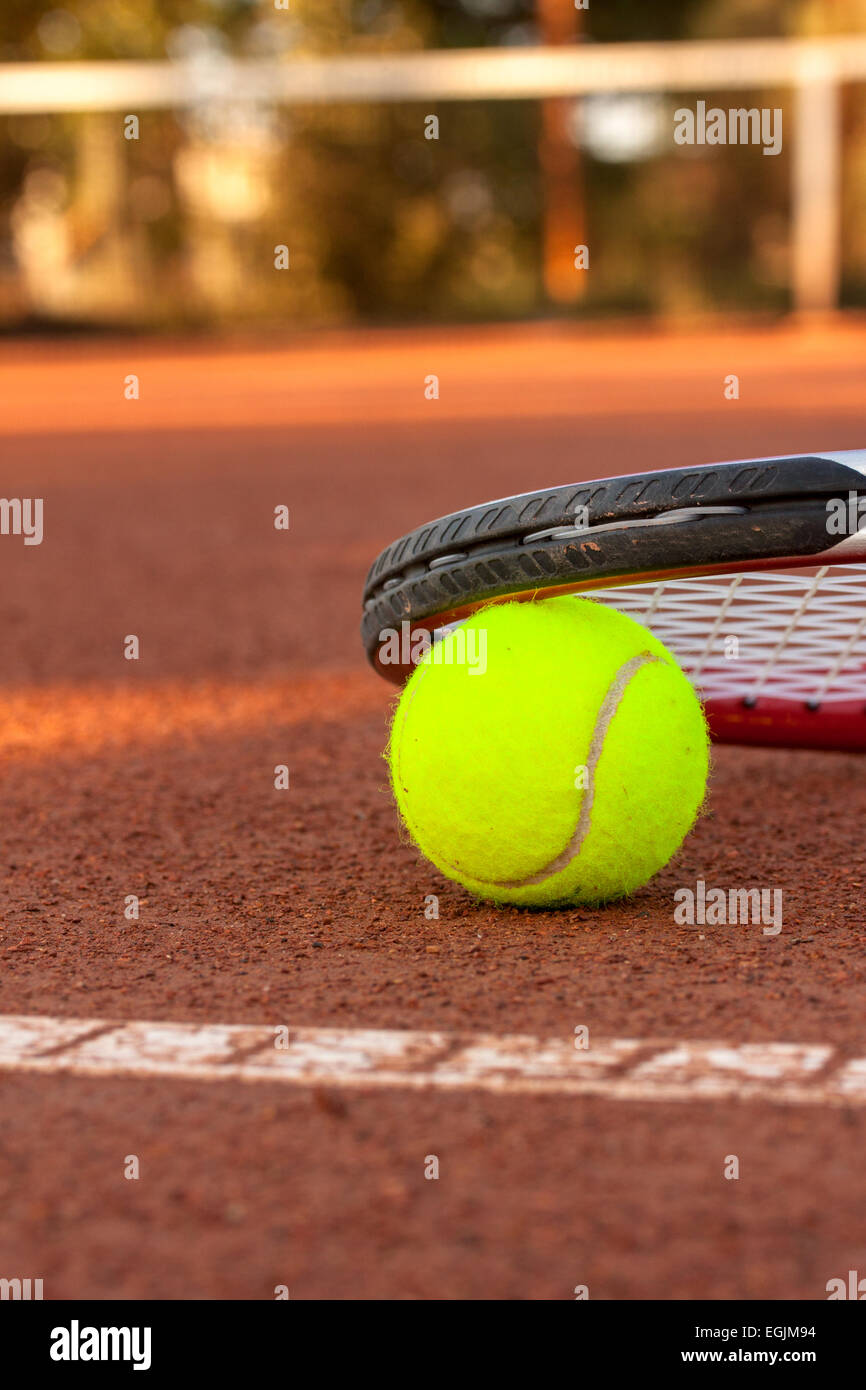 Tennis ball and racquet on a tennis clay court Stock Photo - Alamy