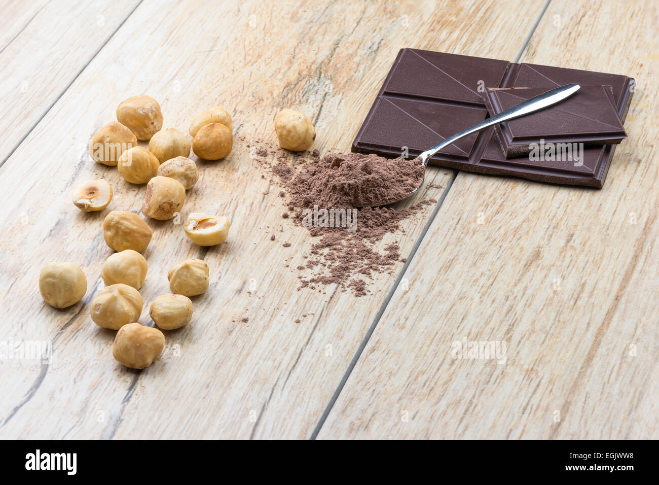 A side view of chocolate, hazelnuts clean and covered teaspoon cocoa ...
