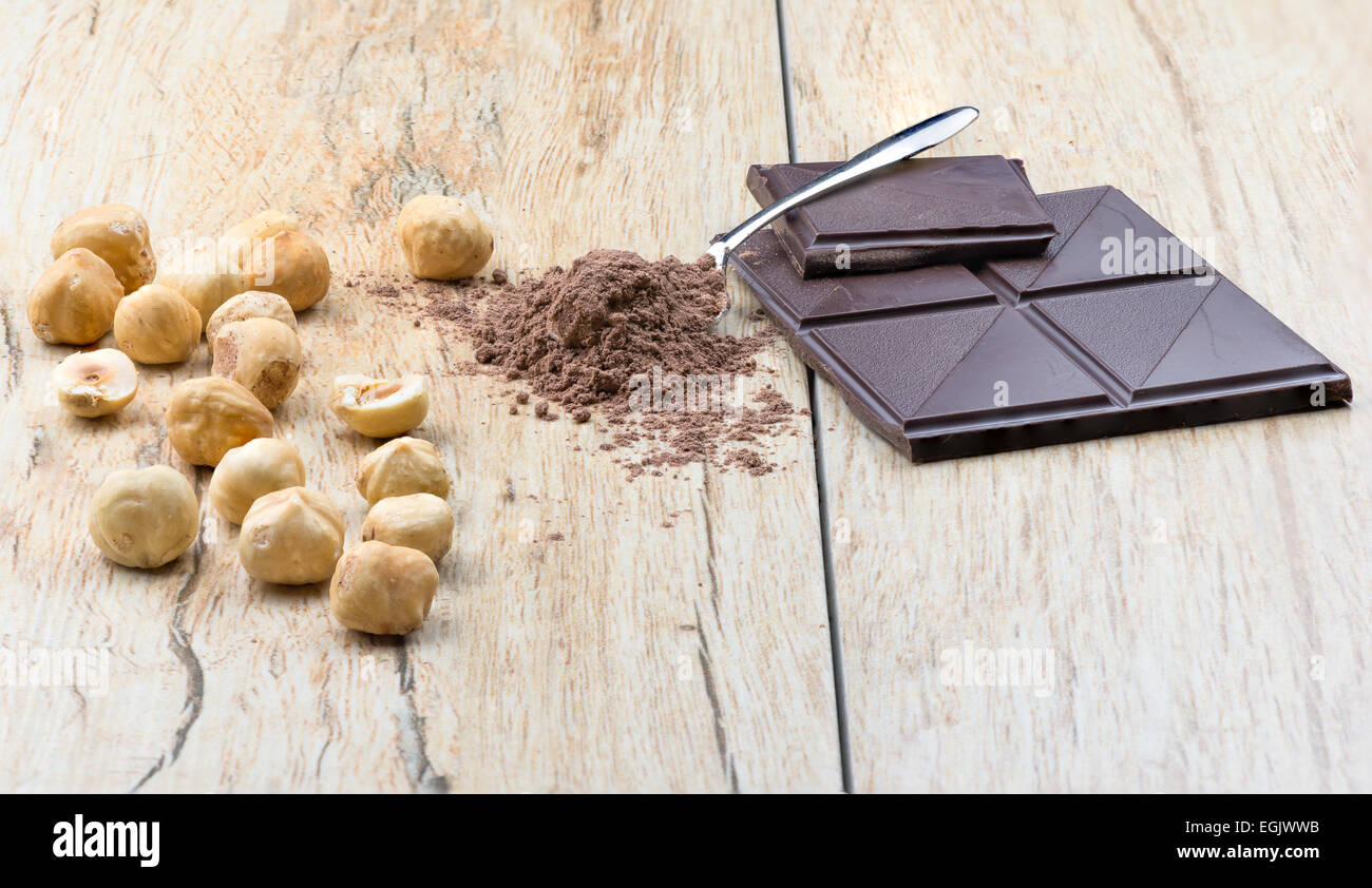 A front view of chocolate, hazelnuts clean and covered teaspoon cocoa ...