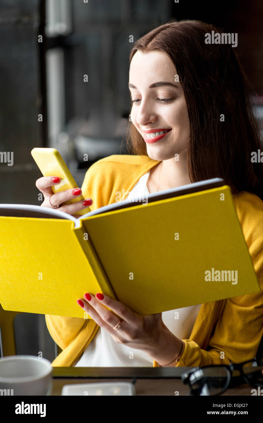 Woman with book and mobile phone Stock Photo - Alamy