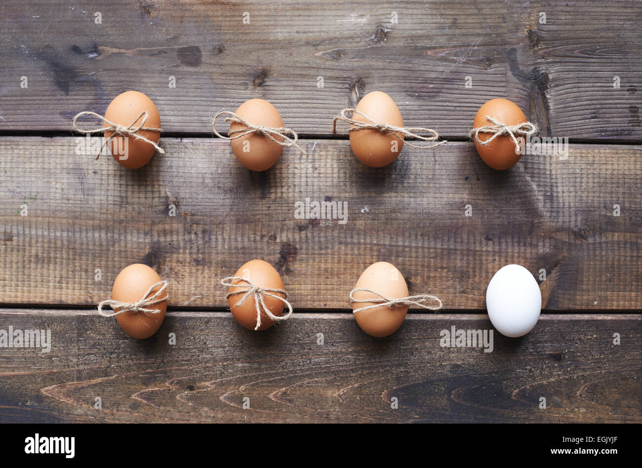 Two rows of eggs tied by threads on wooden background Stock Photo - Alamy