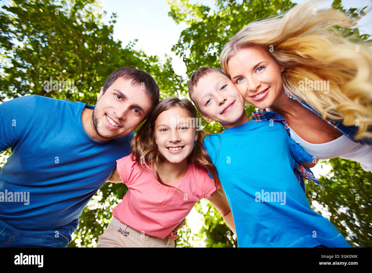 Affectionate kids and parents looking at camera during rest in park ...
