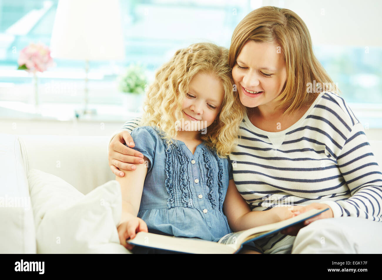 Little girl and her mother reading book together Stock Photo - Alamy