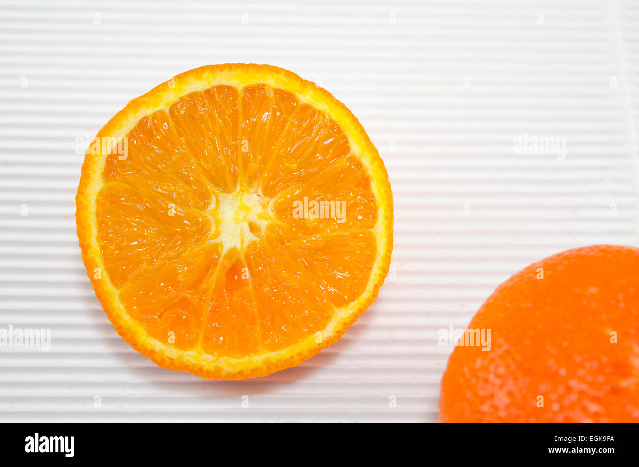 Juicy slice of halved orange on a white cardboard Stock Photo - Alamy