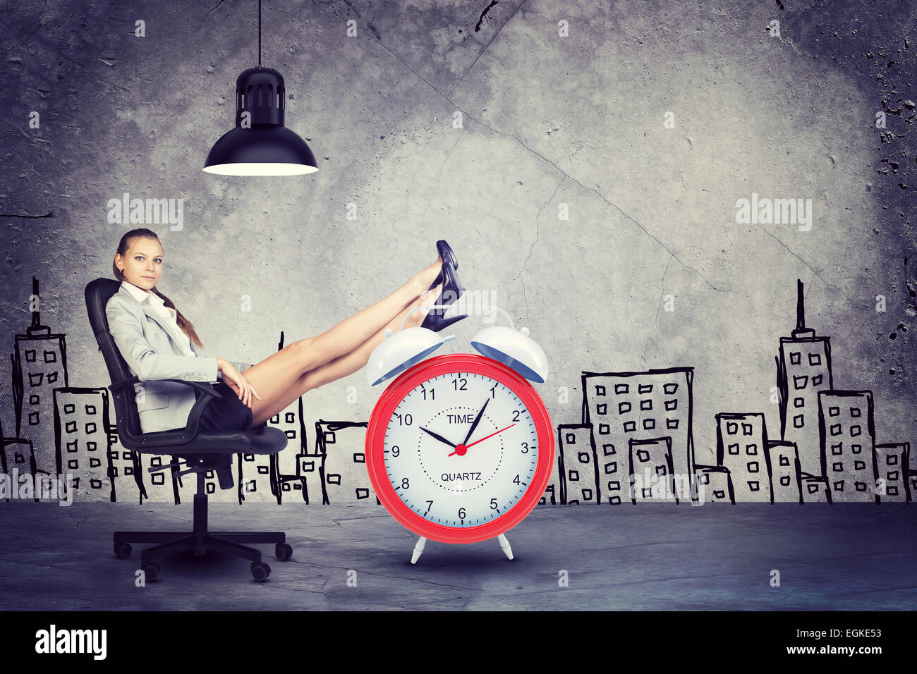 Businesswoman sitting with her feet up on alarm-clock Stock Photo - Alamy