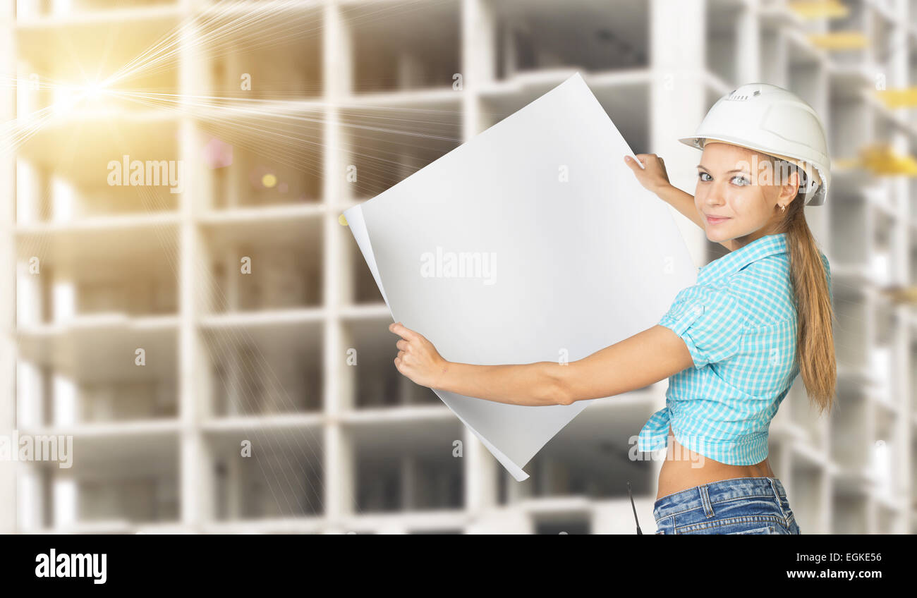 Woman holding blank drawing sheet in front of building under ...