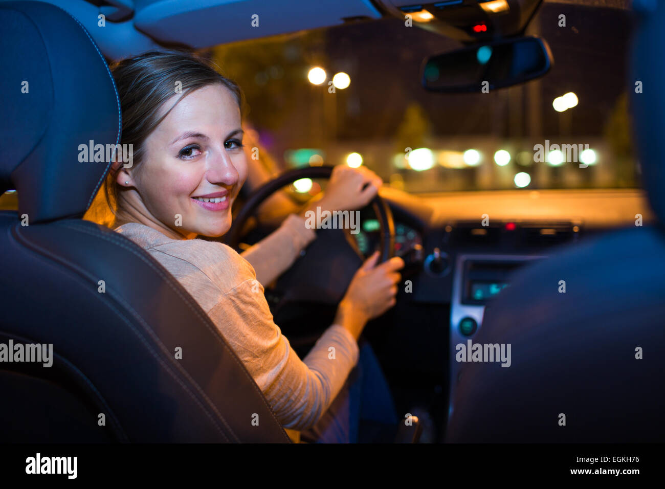 Pretty young woman driving her new car at night Stock Photo - Alamy