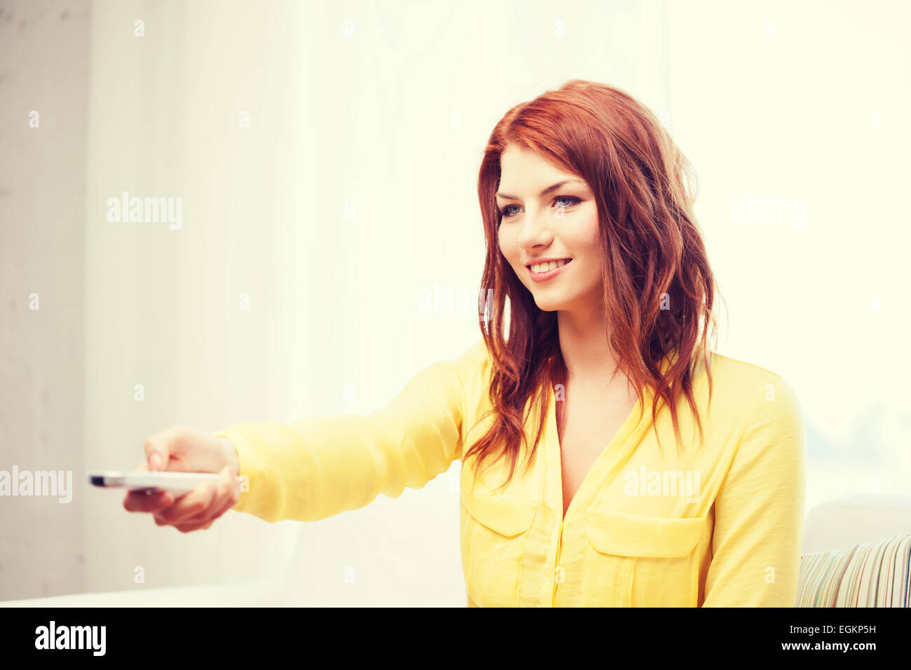 smiling young woman with tv remote control at home Stock Photo - Alamy