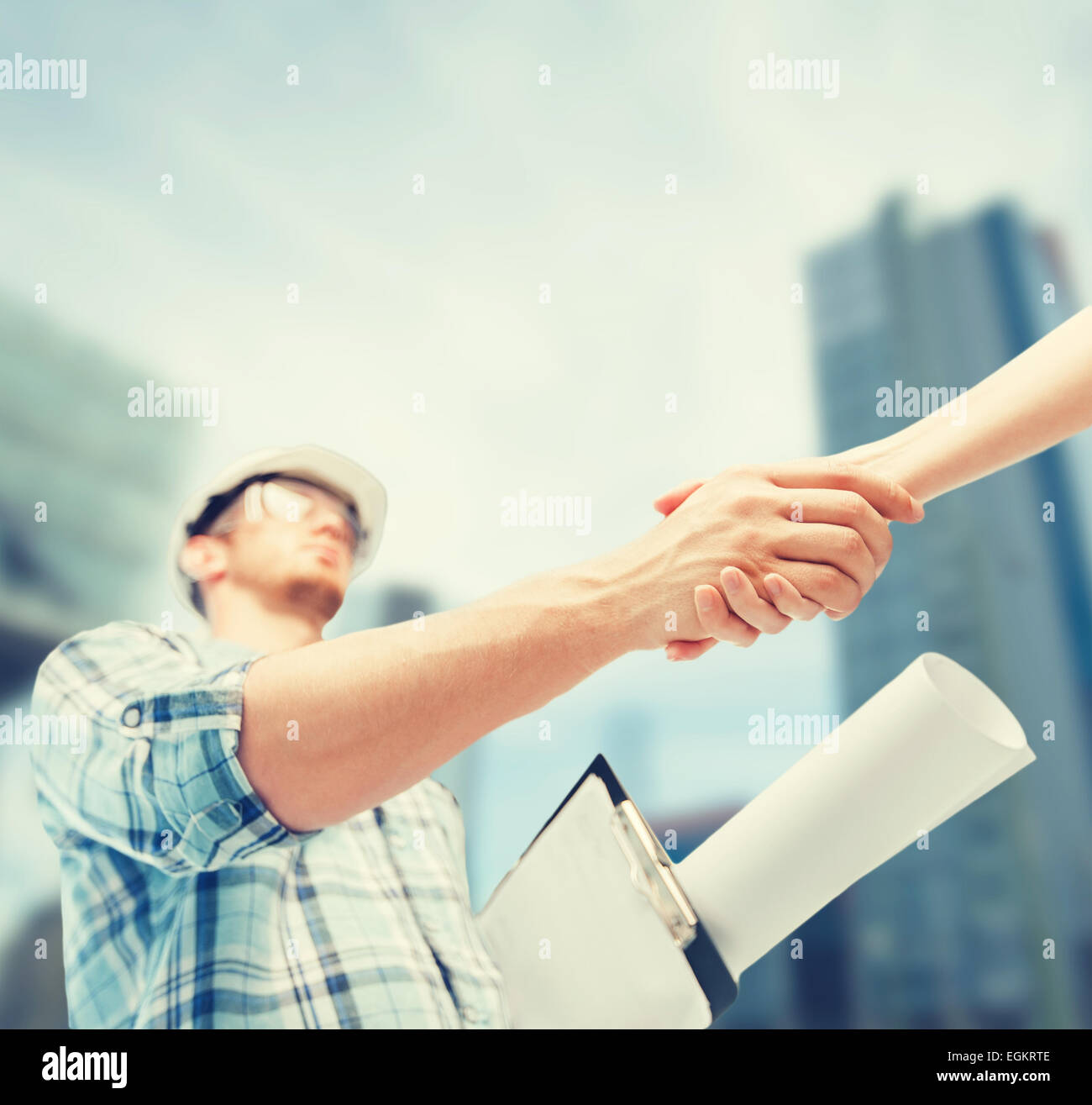 builder with blueprint shaking partner hand Stock Photo - Alamy