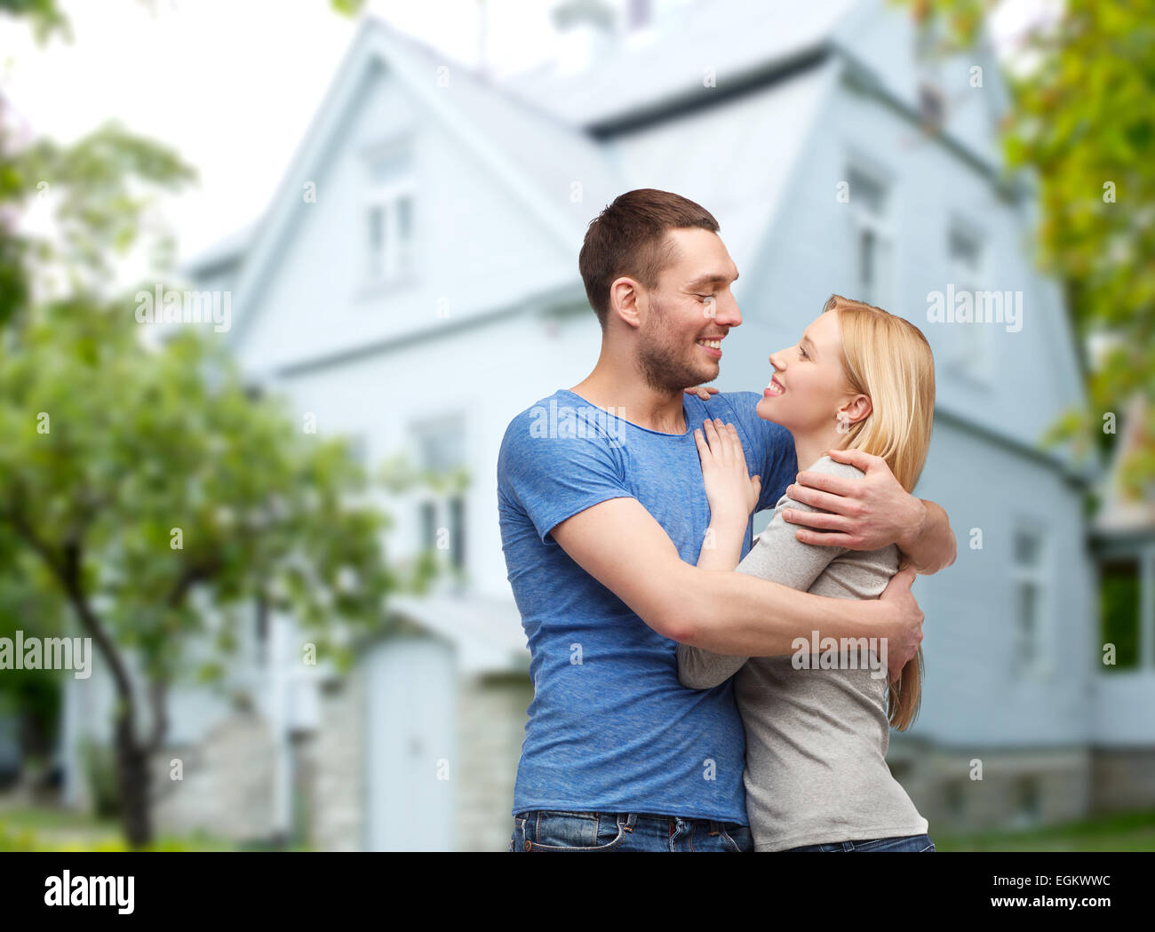 smiling couple hugging over house background Stock Photo - Alamy