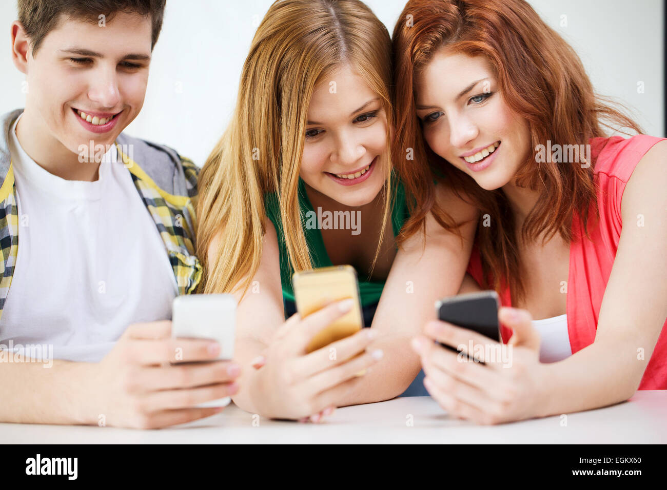 three smiling students with smartphone at school Stock Photo - Alamy