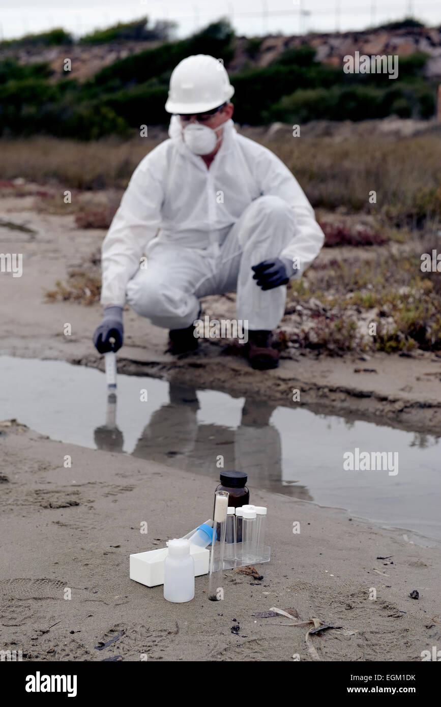 Worker in a protective suit examining pollution in the water at the ...