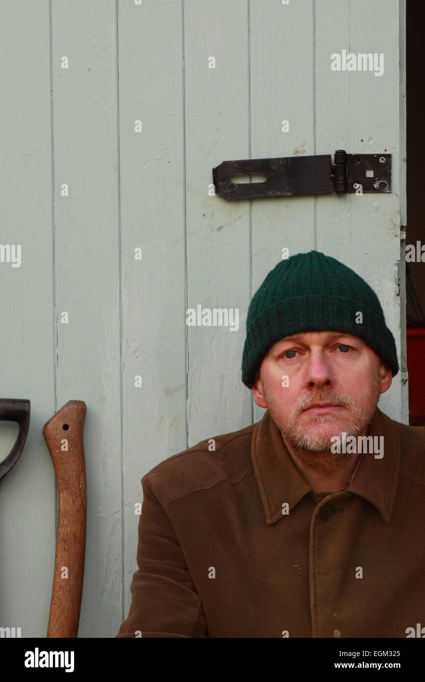 Man aged 50 years outside his shed with tools wearing old working ...