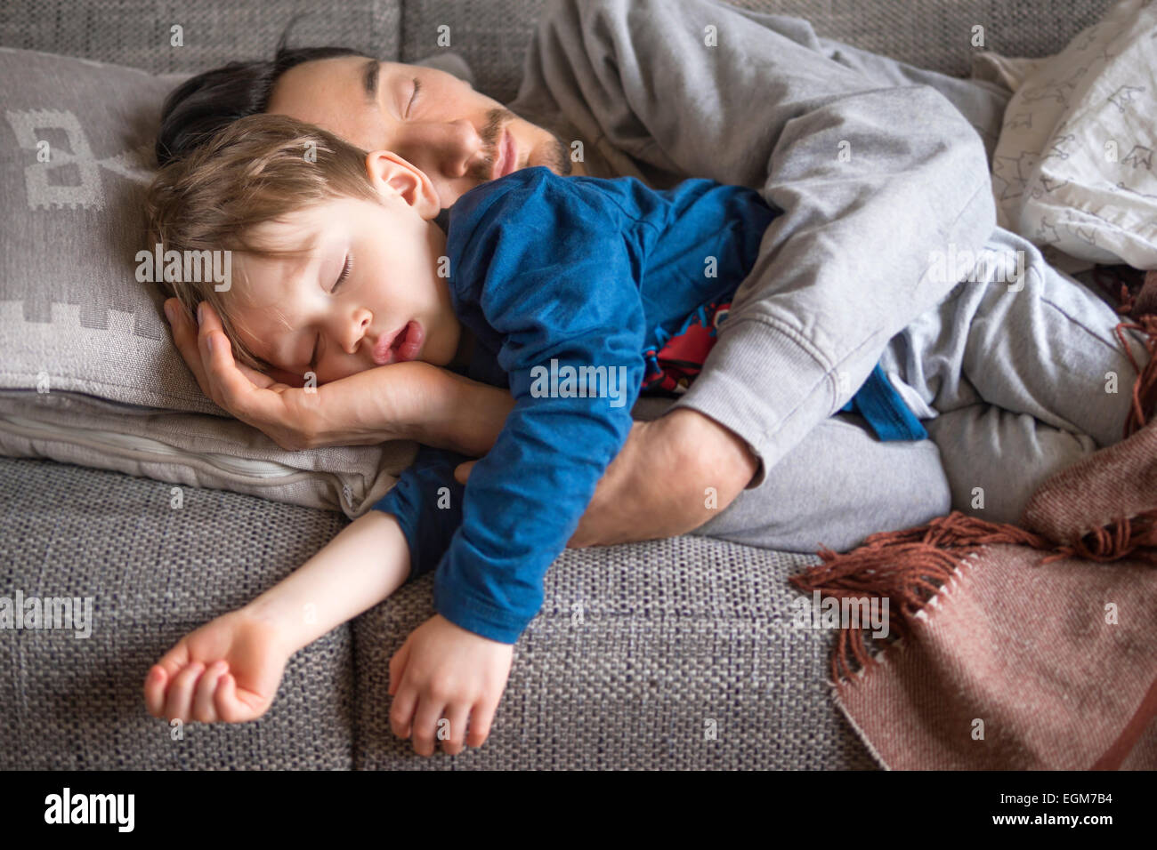 Portrait Of Father And Son Fallen Asleep Together On The Couch Stock