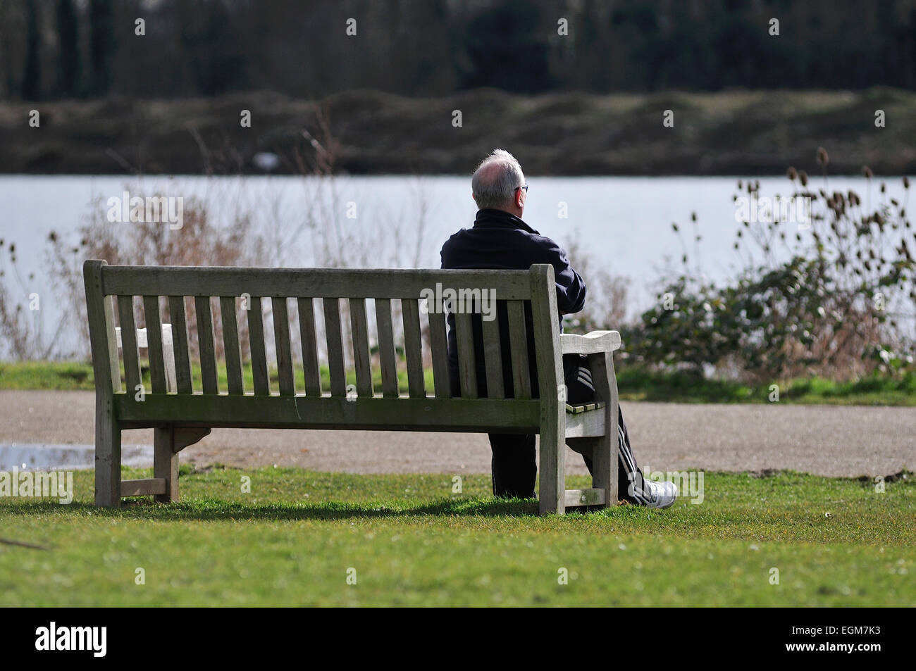 Elderly man sitting alone on a park bench Stock Photo - Alamy
