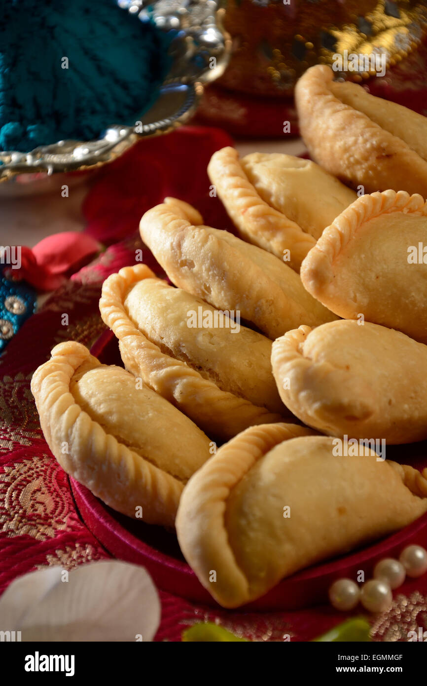 Gujia is a cuisine of India surrounded by colorful gulaal in the bowls ...