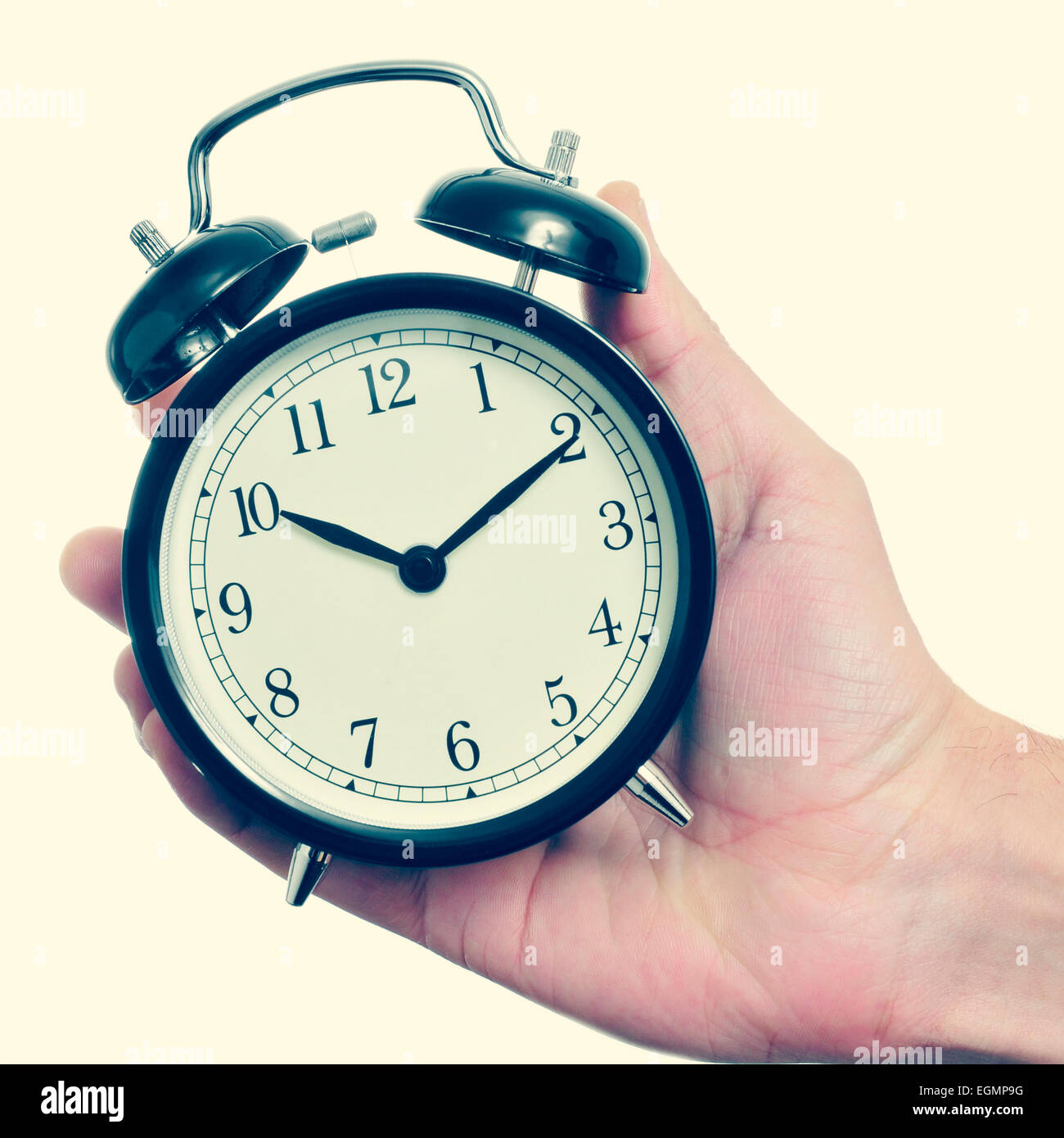 a man holding a mechanical alarm clock in his hand, with a retro effect ...