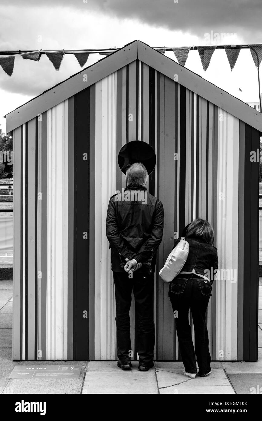 A Couple Look Through The Window Of A Beach Hut Installation, Festival ...