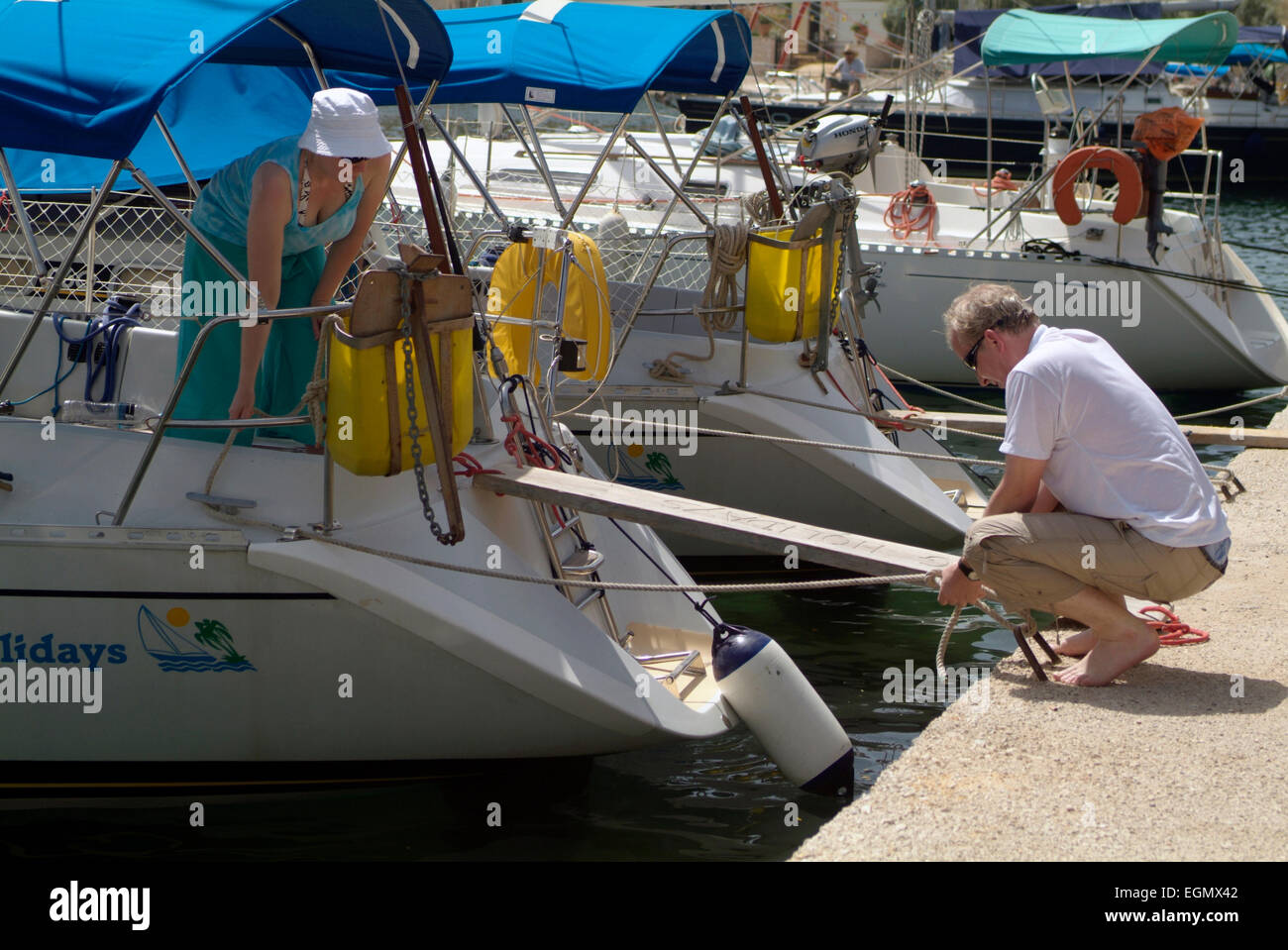 man adjusting mooring rope on sail boat Stock Photo - Alamy