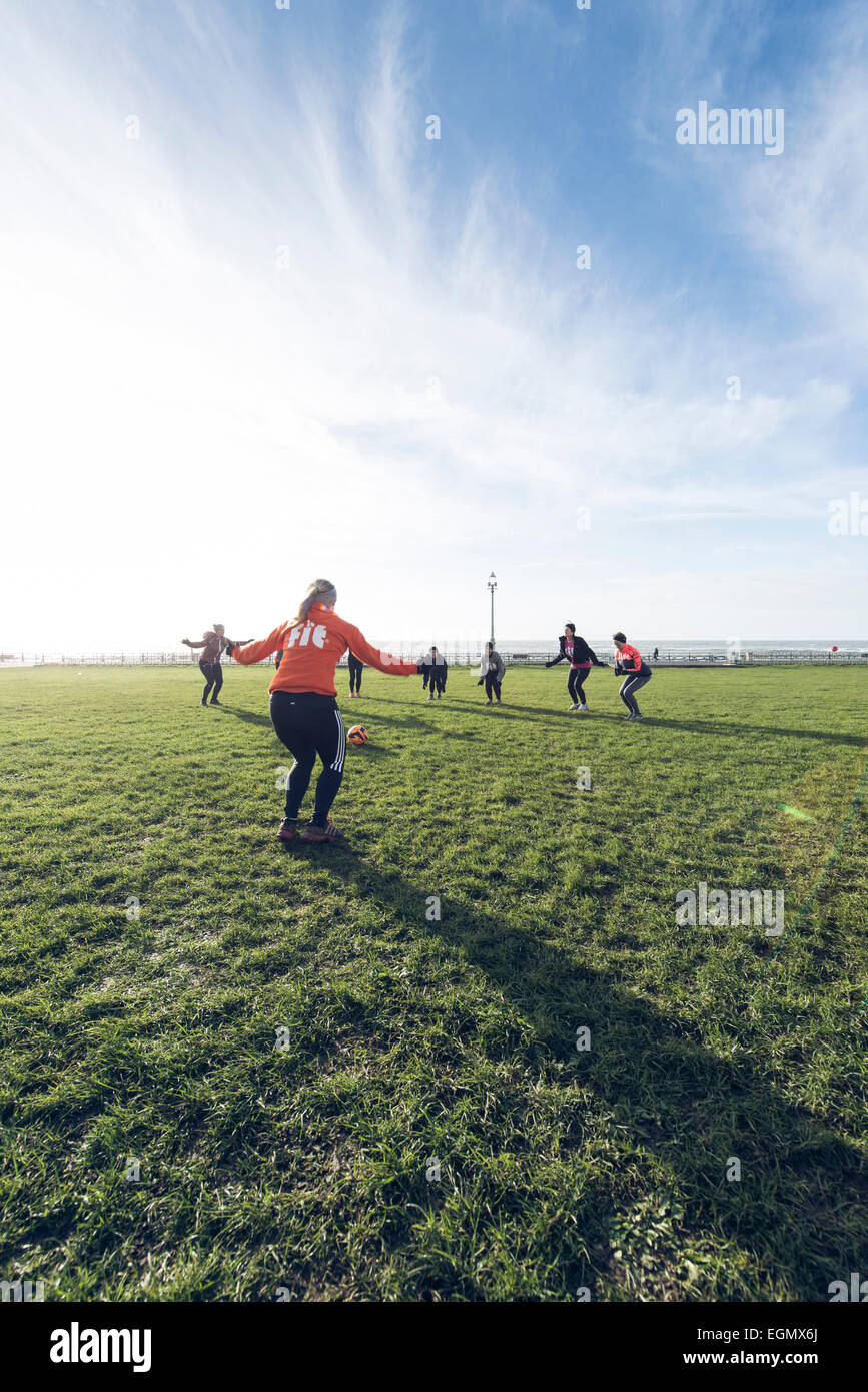 a group of girls / women take part in an out doors group fitness ...