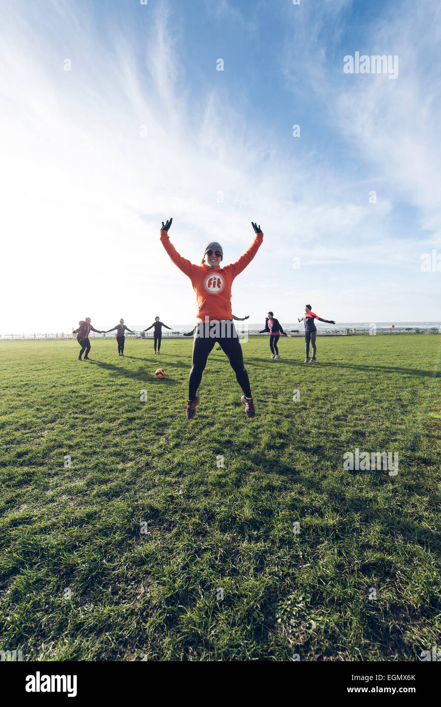 a group of girls / women take part in an out doors group fitness ...