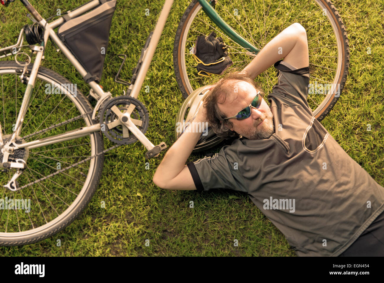 sleeping biker with bicycle in the lawn Stock Photo - Alamy