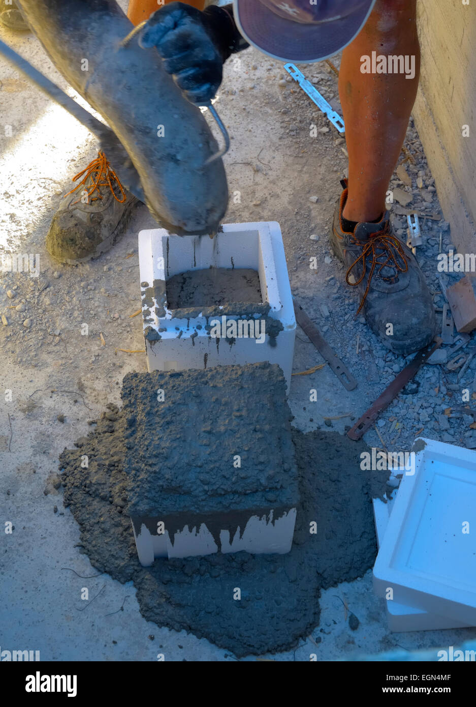 worker prepares the polystyrene mold for concrete test. Focus is on the ...