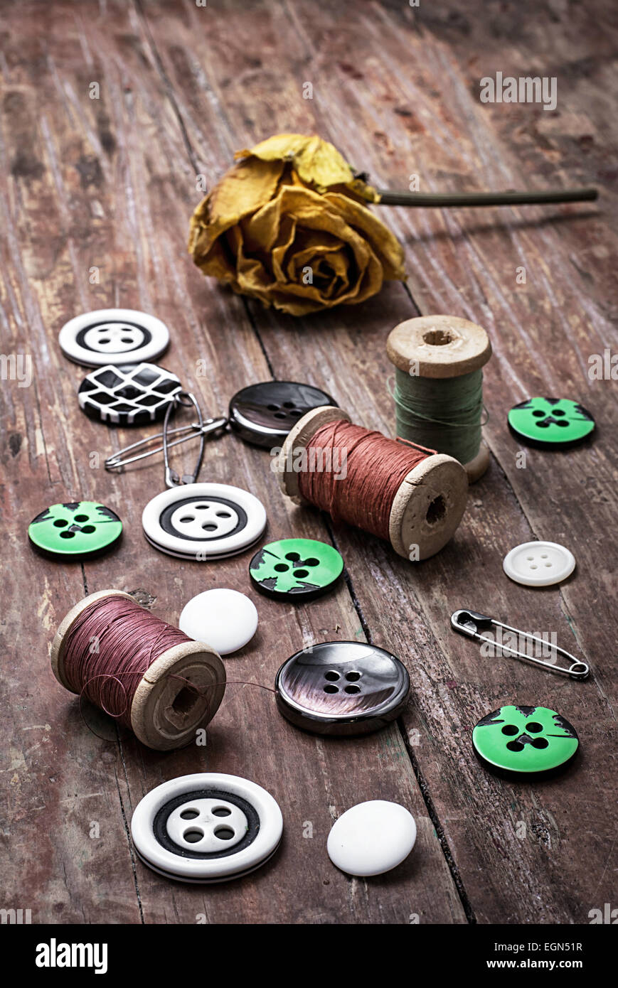 sewing thread, with buttons on wooden background with buds dried yellow ...