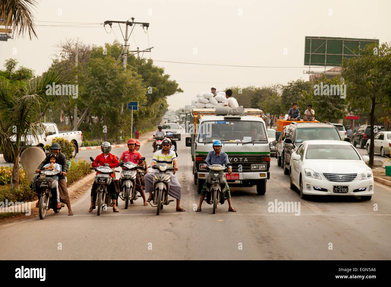 Motorcycles and traffic in a street scene on the road in Mandalay ...